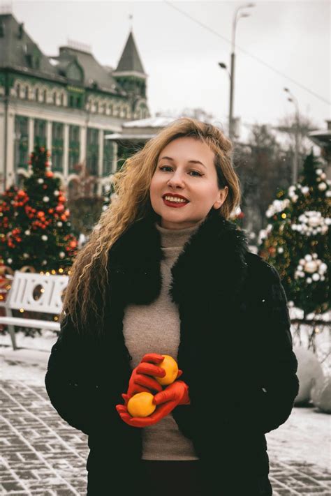 겨울 야외에서 과일을 들고 미소 짓는 여성 · 무료 스톡 사진