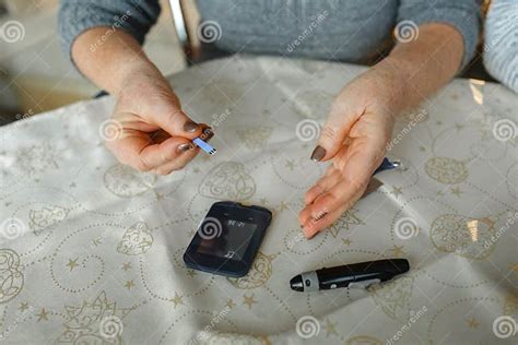 An Elderly Woman Checks Her Blood Sugar Using A Glucometer Stock Image