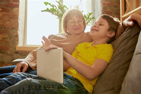 중년 여성과 학령기 소년 할머니와 손자가 집에 앉아 이야기를 나누며 즐거운 시간을 보내고 있습니다 감정 가족 행복 보살핌 지원 및 여가 활동의 개념 2명에 대한 스톡 사진