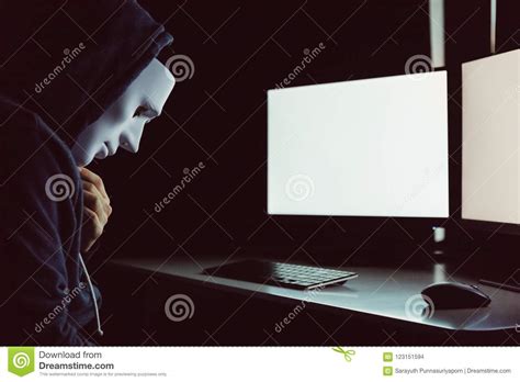 Masked Hacker Under Hood Using Computer To Hack Into System And Trying