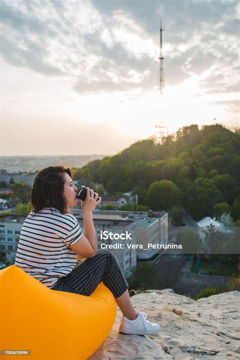 도시에 일몰을 즐기는 커피를 마시는 노란 팽창 식 매트리스에 앉아있는 여자 가장자리에 대한 스톡 사진 및 기타 이미지