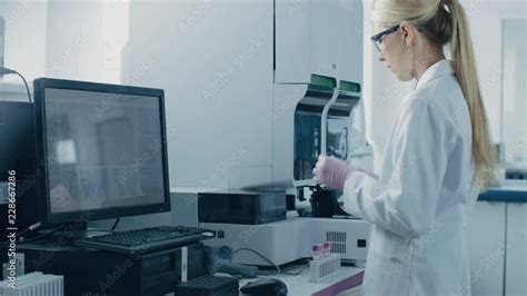 Female Research Scientist Puts Test Tube With Blood Sample Into Medical Analyzing Machine