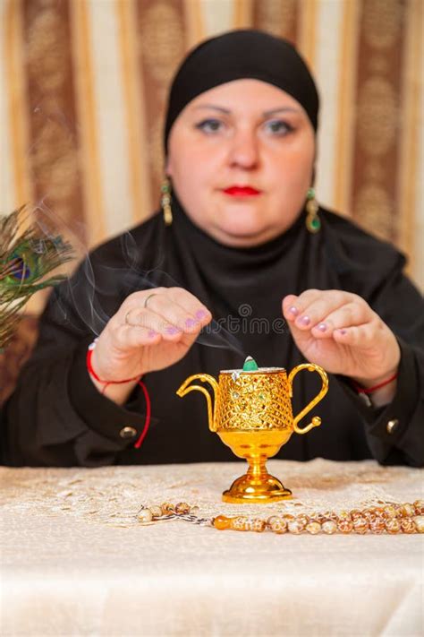 A Muslim Woman In A Black Hijab Makes A Dua At A Table With Incense