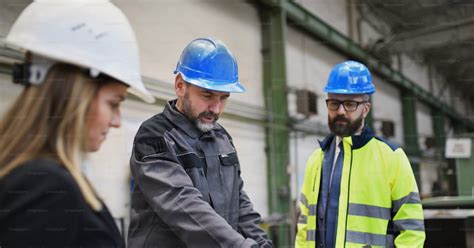 관리자 감독자와 제복을 입은 산업 노동자가 대형 금속 공장 홀에서 통제를 하고 이야기를 나눕니다 사진 Unsplash의 슬로바키아 이미지