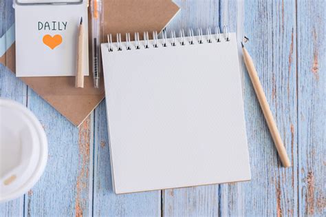 복사 공간이있는 파란색 파스텔 나무 배경에 연필과 커피 컵으로 텍스트와 메시지를 쓰기위한 상단보기 흰색 바인더 빈 노트북 이나