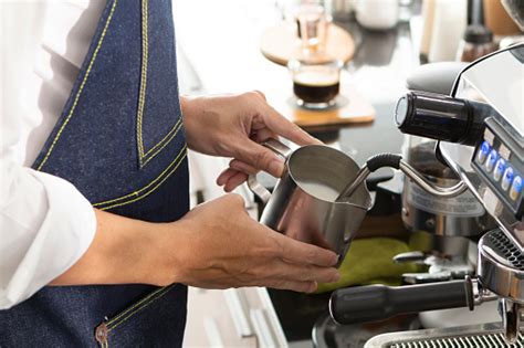 젊은 바리스타 준비 및 커피 머신에스프레소 만들기 바리스타가 커피숍에서 카푸치노를 만드는 것을 보세요 바리스타가 포르타필터를 들고 커피 한 잔을 준비하고 있습니다 기계류에