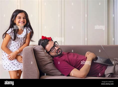 A Playful Daughter Looking At Camera While Teasing Sleeping Father