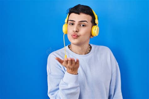 Non Binary Person Listening To Music Using Headphones Looking At The