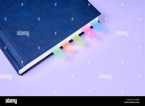 An Office Notepad With Colorful Sticky Page Markers Sandwiched Between Pages On Purple