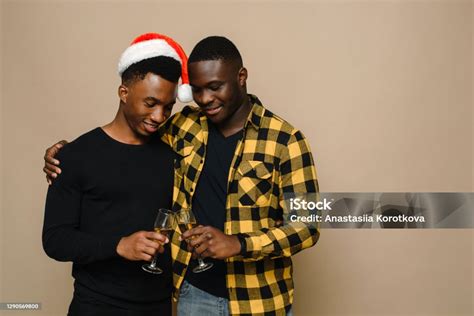크리스마스에 행복한 가족 초상화 베이지 색 배경에 게이 남성 커플 샴페인 을 좋아하는 링크 안경을 쓴 흑인 남성 한 쌍 건배 크리스마스와 새해를 축하 동성애자에 대한 스톡