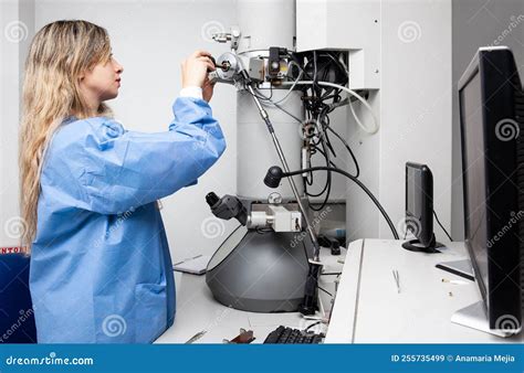 Young Female Scientist Loading A Specimen Using A Sample Holder Into A