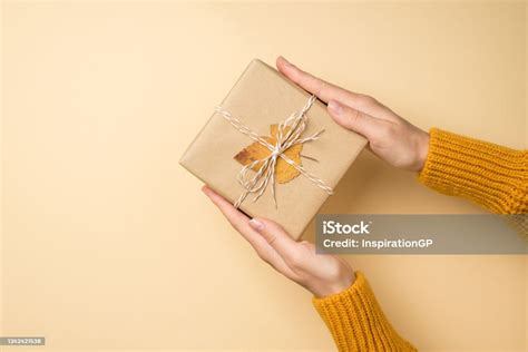 카피 스페이스와 고립 된 베이지 색 배경에 꼬임 활과 노란색 가을 잎 공예 종이 선물 상자를 들고 노란색 스웨터에 손의 1 인칭 상단 보기 사진 10월에 대한 스톡 사진 및