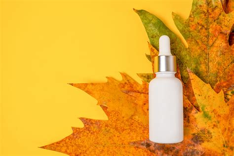 노란색 배경에 건조한 낙엽이있는 흰색 화장품 점적기 병 가을 작곡 천연 및 유기농 스킨케어 제품의 개념 강단에 대한 스톡 사진 및 기타 이미지 Istock