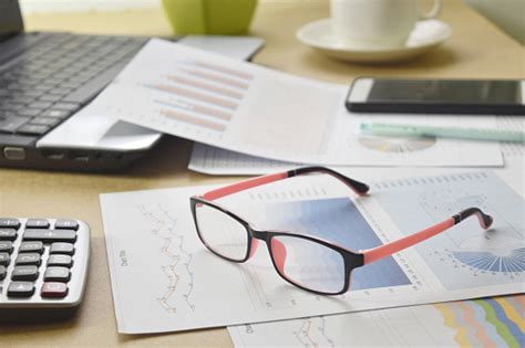 그래프와 차트를 볼 수 있습니다 비즈니스 보고서 및 커피 컵 안경 스마트 폰 책상에 계산기 장소와 문서의 더미 0명에 대한 스톡