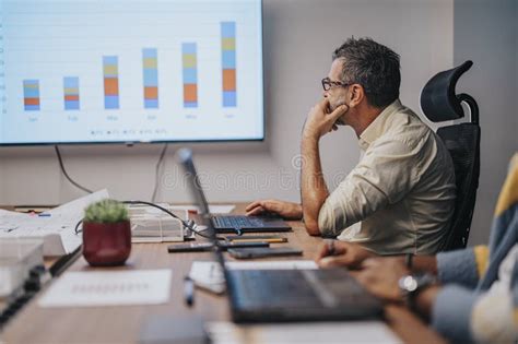 Collaborative Business Meeting Discussing Architectural Blueprints And Graph Charts Multiracial