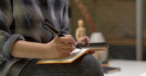 여성 노동자가 작업대에 앉아 스마트폰으로 보면서 빈 일정표에 메모하는 장면 사진 Unsplash의 태국 이미지