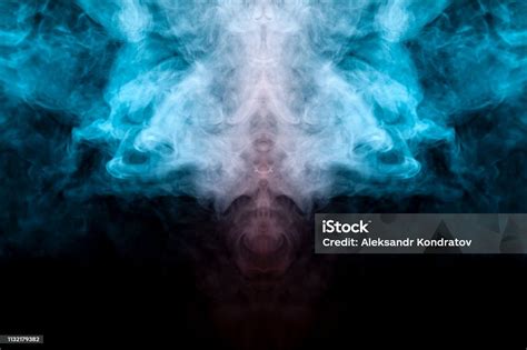 큰 눈과 공포 영화에서 검은 고립 된 배경에 공포의 느낌을 만드는 열린 입으로 유령 얼굴의 모양에 녹색 파란색과 분홍색 색깔의 연기의 신비 패턴 개념에 대한 스톡 사진 및