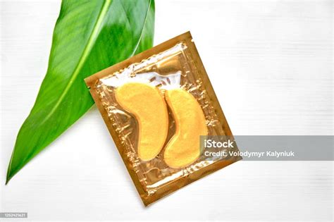 녹색 잎이 있는 흰색 배경에 금 콜라겐 아이 마스크 또는 패치 스킨 케어와 뷰티 컨셉 건강관리와 의술에 대한 스톡 사진 및 기타 이미지 건강관리와 의술 금색 노화