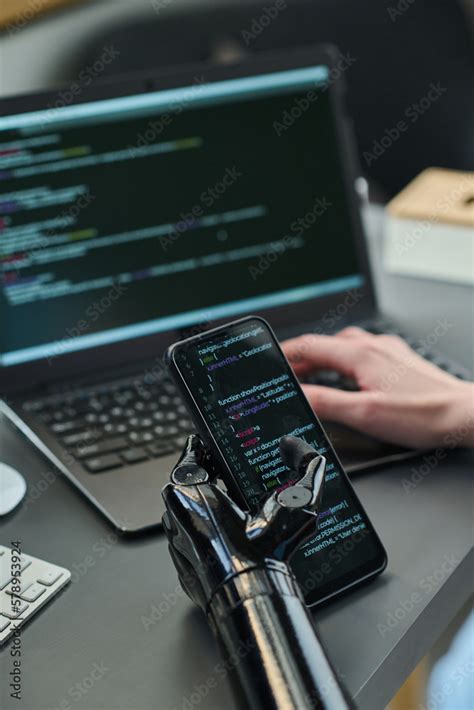 Vertical Image Of Programmer With Prosthetic Arm Connecting Smartphone