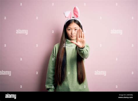Young Asian Woman Wearing Cute Easter Bunny Ears Over Pink Background