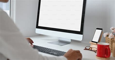 작업 공간에서 흰색 화면이 있는 컴퓨터와 스마트폰으로 작업하는 청년의 잘린 샷 사진 Unsplash의 올인원 이미지