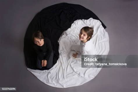 검은 색과 흰색 옷을 입은 두 명의 아이들이 음 양 원의 바닥에 누워 있습니다 2명에 대한 스톡 사진 및 기타 이미지 2명