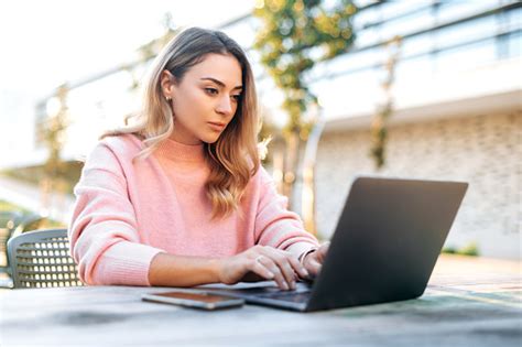 똑똑하고 자신감 넘치는 성공적인 백인 젊은 여성 Seo 프리랜서 회사 직원 야외 테이블에 앉아 노트북으로 작업하며 새로운 디지털 프로젝트의 잠재력을 탐구합니다 노트북에 대한