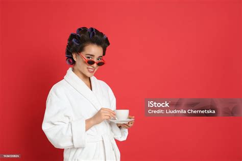 목욕 가운을 입은 행복한 젊은 여자는 머리 컬러와 선글라스를 끼고 빨간색 배경에 음료수 컵을 들고 있다 20 24세에 대한 스톡 사진 및 기타 이미지 Istock