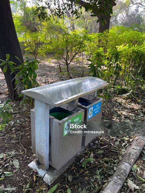 공원에 두 개의 구획이 있는 금속 쓰레기통에 있는 쓰레기 재활용 로고의 이미지 음식 및 플라스틱 쓰레기통 섹션 녹색 및 파란색 플라스틱 폐기물 양동이 전경에 초점 쓰레기