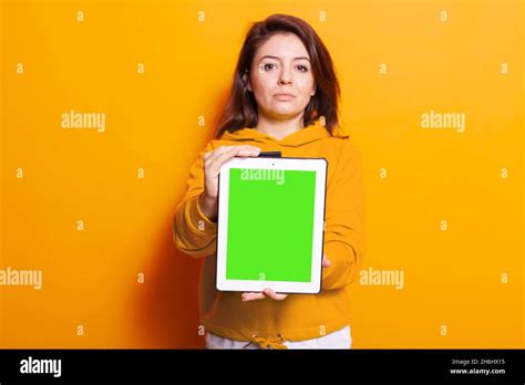 Young woman showing tablet with vertical green screen on camera. Modern person holding digital ...
