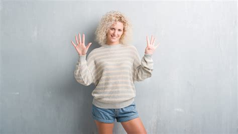 그런 지 회색 배경에 표시 하 고 손가락으로 가리키는 곱슬 머리를 가진 젊은 금발의 여 자가 번호 9 자신감과 행복 미소 하는 동안 가리키기에 대한 스톡 사진 및 기타