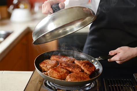 부엌에 있는 요리사는 증기와 철판에 신선한 돼지고기 스테이크를 준비 메뉴는 요리 요리법을 조리 합니다 레스토랑 메뉴 맛 있는 음식 조리법 및 요리 고기에 대한 스톡 사진 및