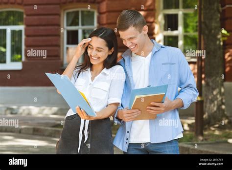 Cheerful Couple Of University Friends Laughing Outdoors While Checking