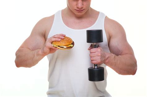 햄버거와 뚱뚱한 남자는 흰색 절연 아령을 보유 하고있다 해로운 음식과 건강 한 라이프 스타일 선택의 개념 건강 한 식사 버 릇과 체중 사람의 초상화입니다 정크 식사 비만으로