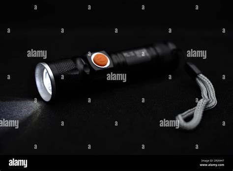 Metal Black Flashlight On A Black Background Burning Pocket Flashlight