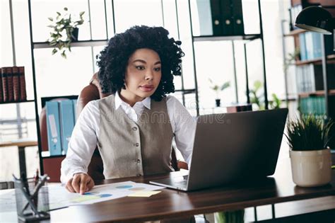 Confident Young Businesswoman Working At Her Office Desk Wearing A