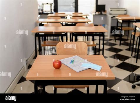 Desk With An Apple Medical Mask And A Copybook In An Empty Classroom