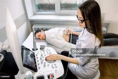 클리닉에서 초음파 기계로 작업하는 직업 여성 초음파 치료사 여성 환자를위한 신장 초음파 만들기 화면을보고 제어판에 버튼을