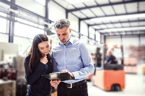 Female Warehouse Manager Talking With Logistics Employee In Warehouse Planning Transport Of