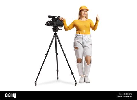 Full Length Portrait Of A Female Camera Operator With A Camera On A Tripod Stand Gesturing