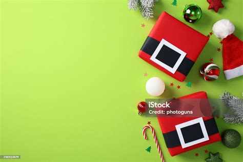 빨간 선물 상자와 크리스마스 녹색 배경 장식 산타 벨트 사탕 지팡이 축제 장식품 싸구려 산타 모자 전나무 가지 색종이 조각 플랫 레이아웃 평면도 복사 공간 12월에 대한