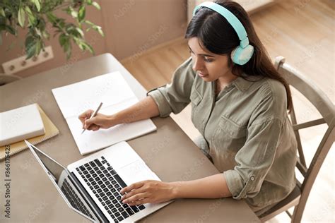 Indian Girl Student Wear Headphones Learning Online Watching Webinar Class Looking At Laptop