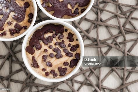 바나나와 코코넛 크림의 생 과일 아이스크림을 고리버들 식탁보에 흰 종이 컵에 천연 초콜릿 방울과 함께 닫습니다 건강한 비건