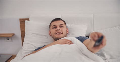 파란색 티셔츠를 입은 잘생긴 백인 남성이 웃으며 침대에서 휴식을 취하고 있다 사진 Unsplash의 피곤한 이미지