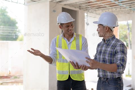 Two Asian Male Engineers Are Inspecting A Job Site And Looking At Drawings Consulting And