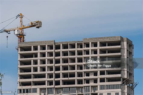 노출된 콘크리트 벽과 금속 프레임 구조로 공사 중인 미완성 다층 건물 두 개의 크레인이 보이며 하나는 노란색이고 다른 하나는 더