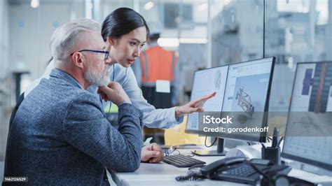 공장 사무실 시설 컴퓨터 Cad 소프트웨어에서 중공업 기계 부품의 청사진을 작성하는 산업 엔지니어 아시아 여성 기술자가 중년 디자이너와의 작업에 대해 논의합니다 컴퓨터 보조