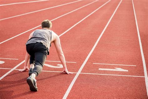 Männlicher läufer, der den sprint von der startlinie startet ...