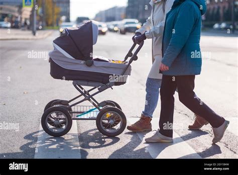 Legs Of Two Women With Stroller On Crosswalk Crossing The Road Stock