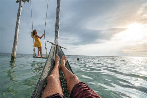 젊은 커플 바다 아름 다운 전원적인 풍경에 의해 해변에 스윙 사람들이는 로맨스 휴가 개념 여행 바다 해먹에 인간과 바다 스윙에